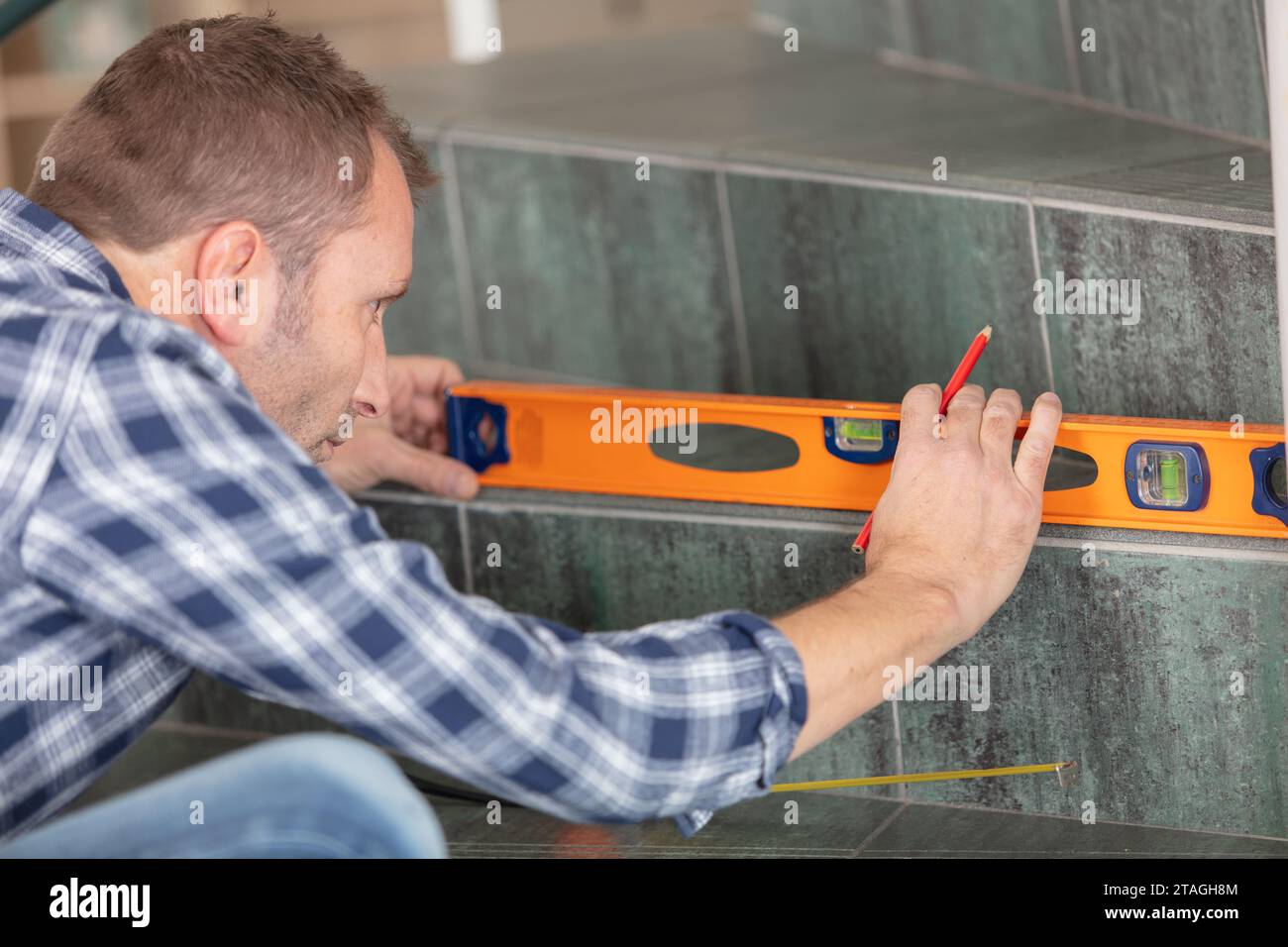 handyman measuring wall for bathroom renovation Stock Photo - Alamy