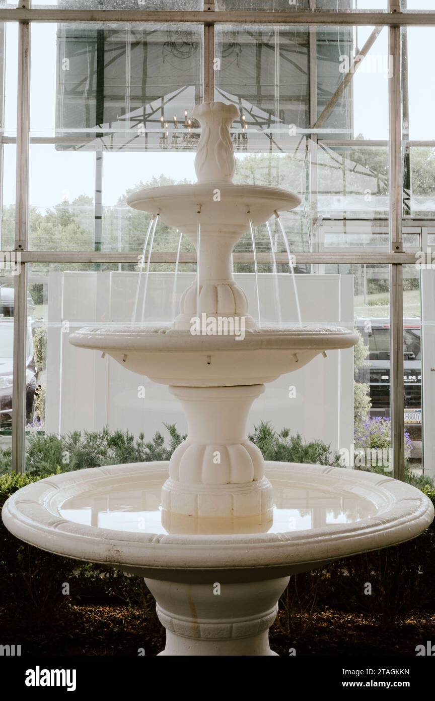 A stunning view of an elegant white fountain in front of a large window ...