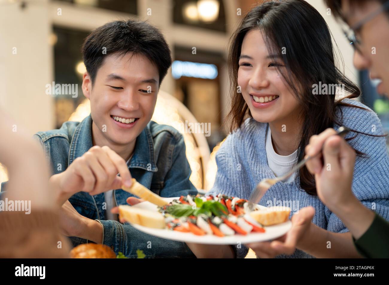 Group of cheerful and joyful young Asian friends enjoying eating food ...