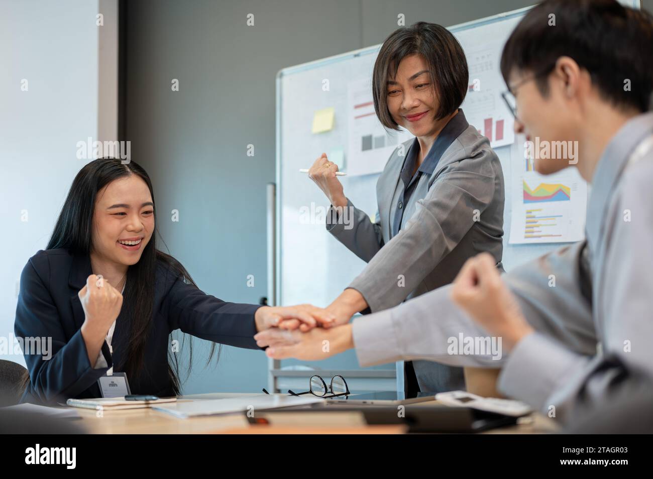 Group of diverse businesspeople are putting their hands together above a meeting table. teamwork ...