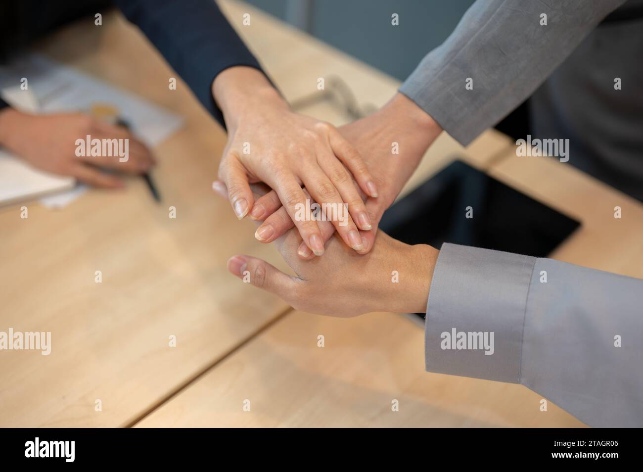 Close-up image of a group of diverse businesspeople are putting their hands together above a ...