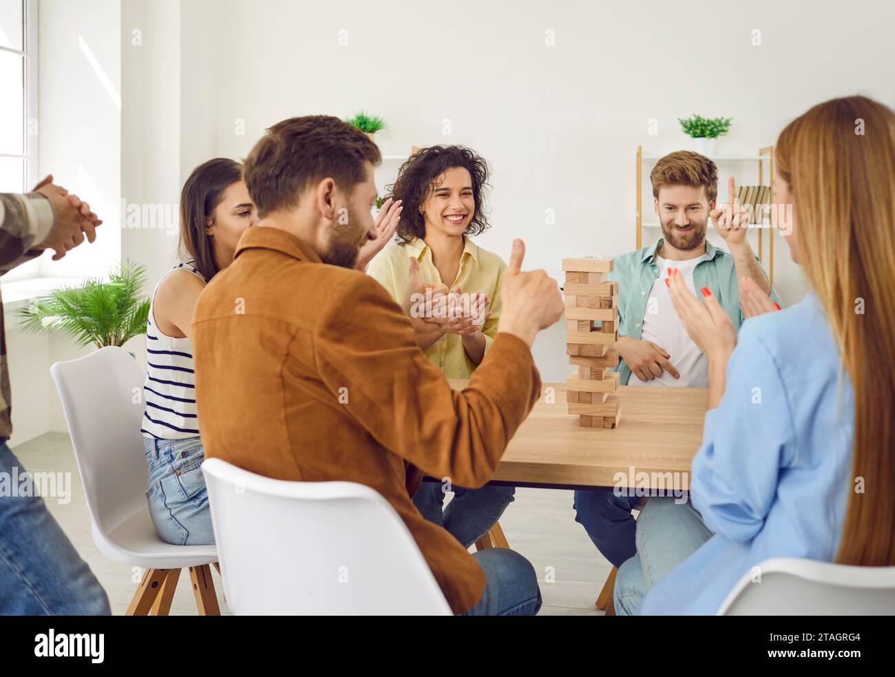 Happy friends playing together with wooden building blocks at home ...