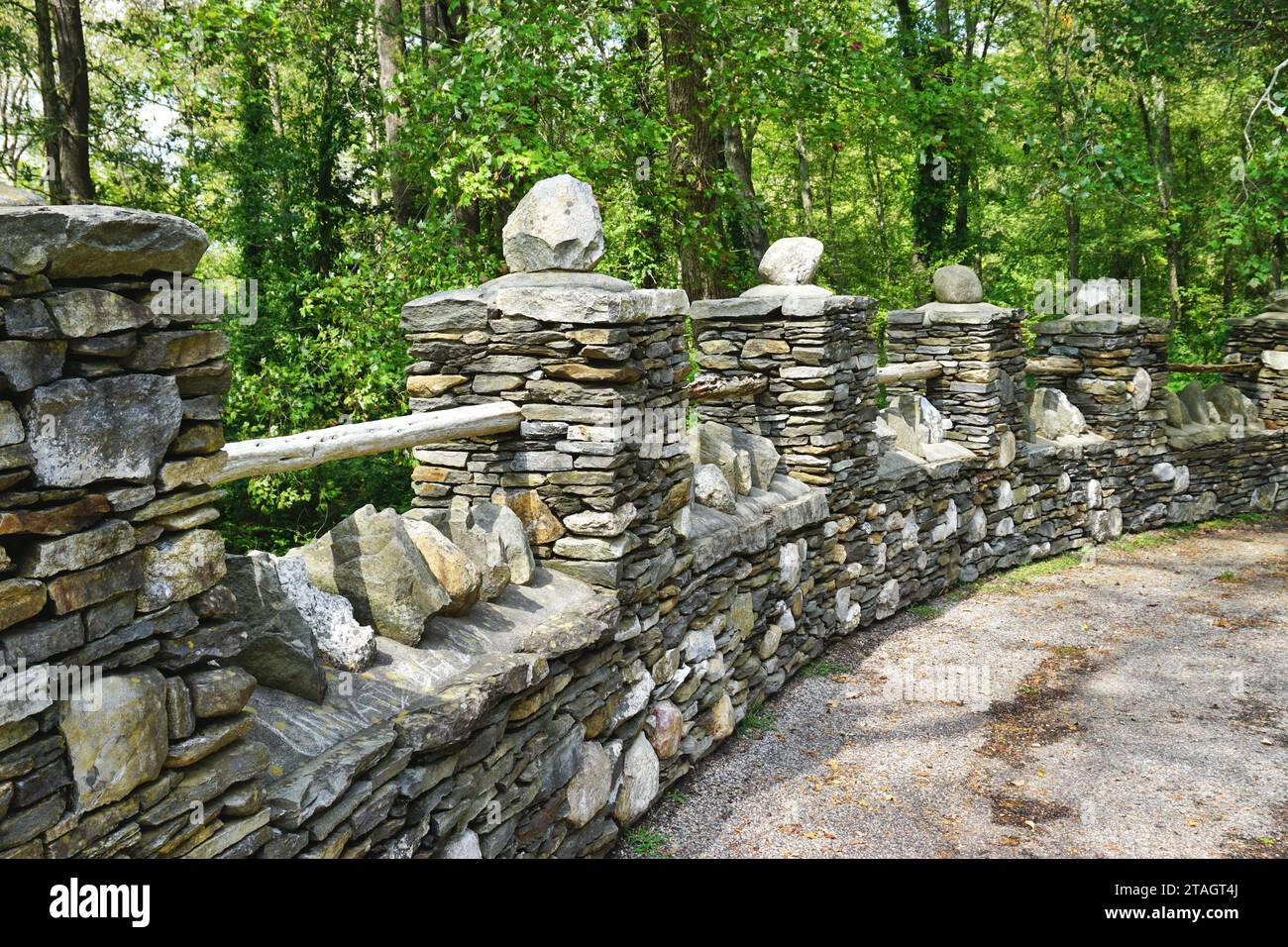 A vintage stone barrier made with stacked dry fieldstones and logs ...