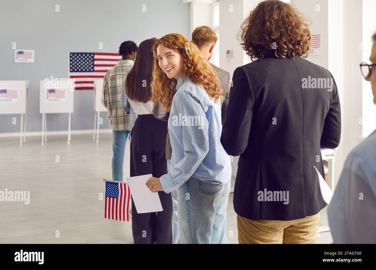 Young happy female american voter standing in a queue at vote center ...
