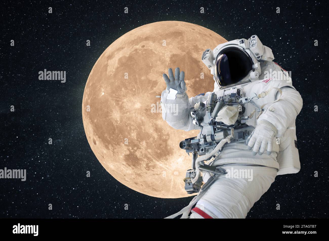 Space man astronaut greets and waves his hand in space on a background ...