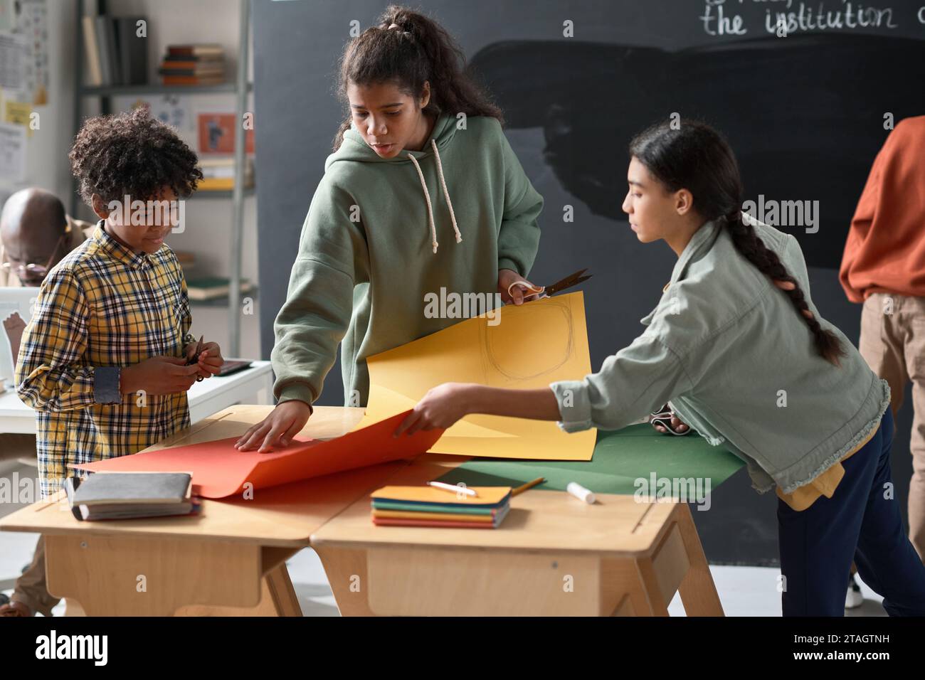 Group of children making craft work from colorful papers together ...
