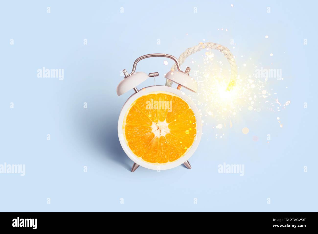 Creative vintage alarm clock orange bomb with wick and sparks on a blue ...