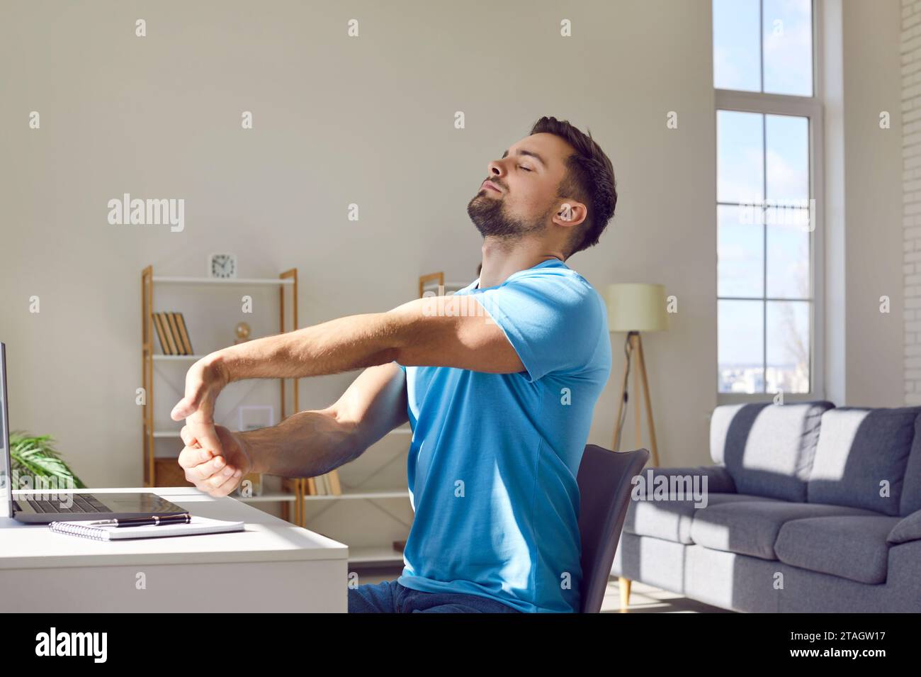 Working man takes a break and does stretching exercise for his arms and ...