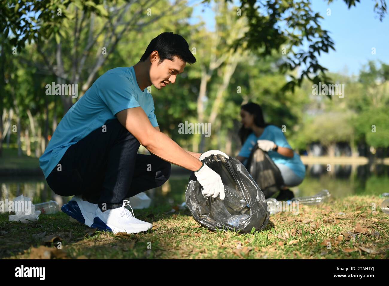 Male volunteer collecting garbage at the public park. Collaboration ...
