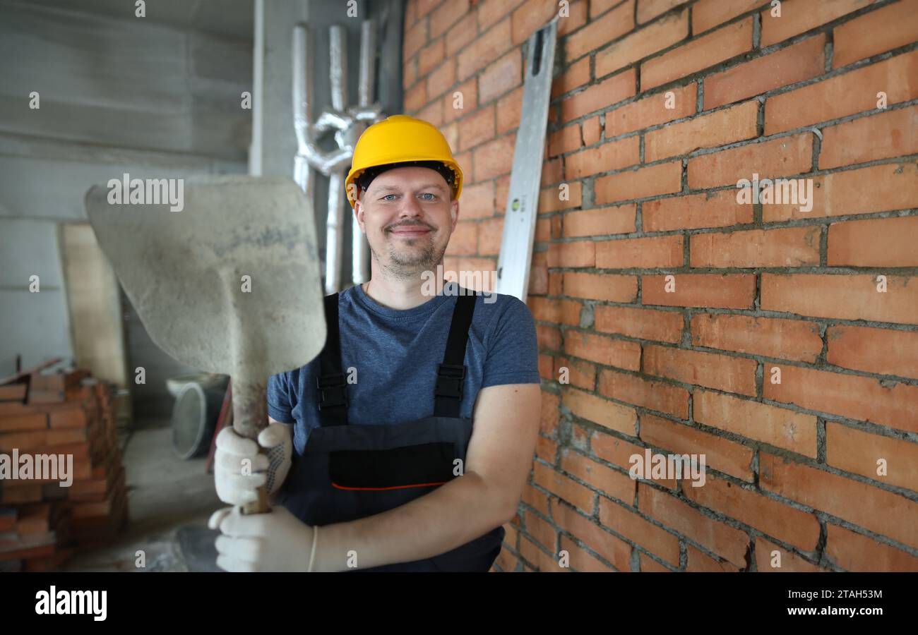 Worker in hard hat holds cement shovel Stock Photo - Alamy