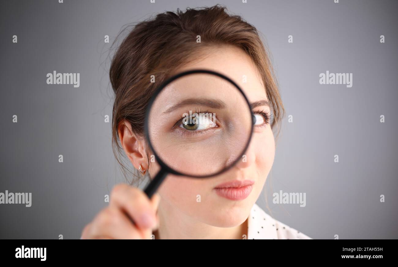 Inquisitive young woman looking through magnifying glass Stock Photo ...