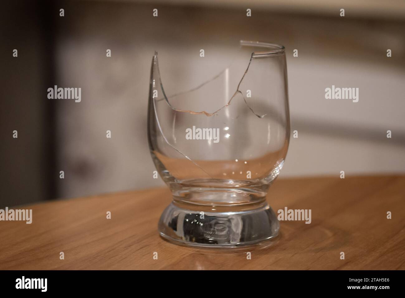 Broken transparent drinking glass on the table. Sharp dangerous pieces ...