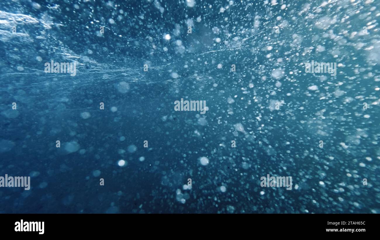 Air bubbles rising from the sea bottom to the water's surface, enhanced ...