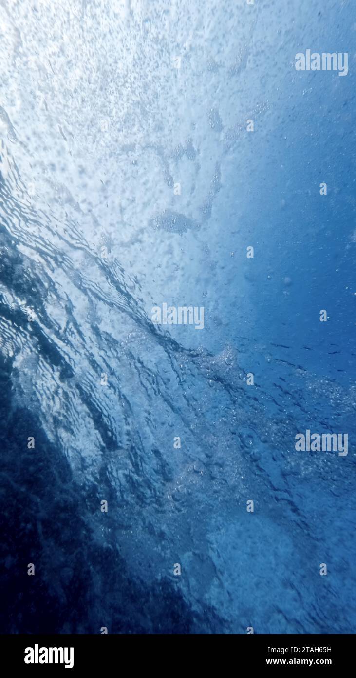 Water ripples and rising air bubbles on the sea surface shot underwater ...