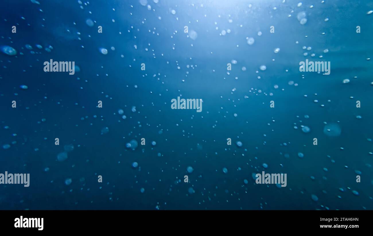 Underwater shot of sun rays shining through clear sea water with rising ...