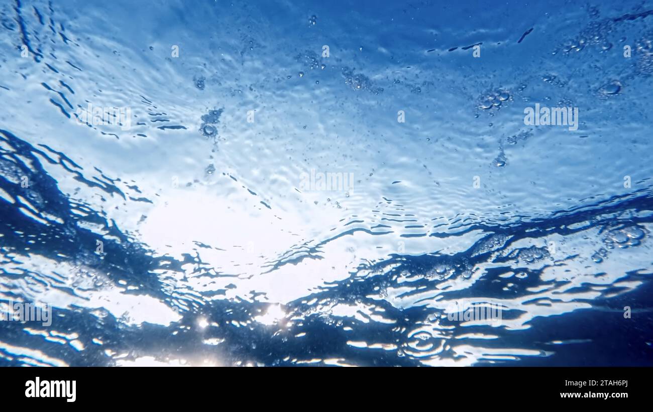Underwater image of sun shining through sea water ripples and air ...
