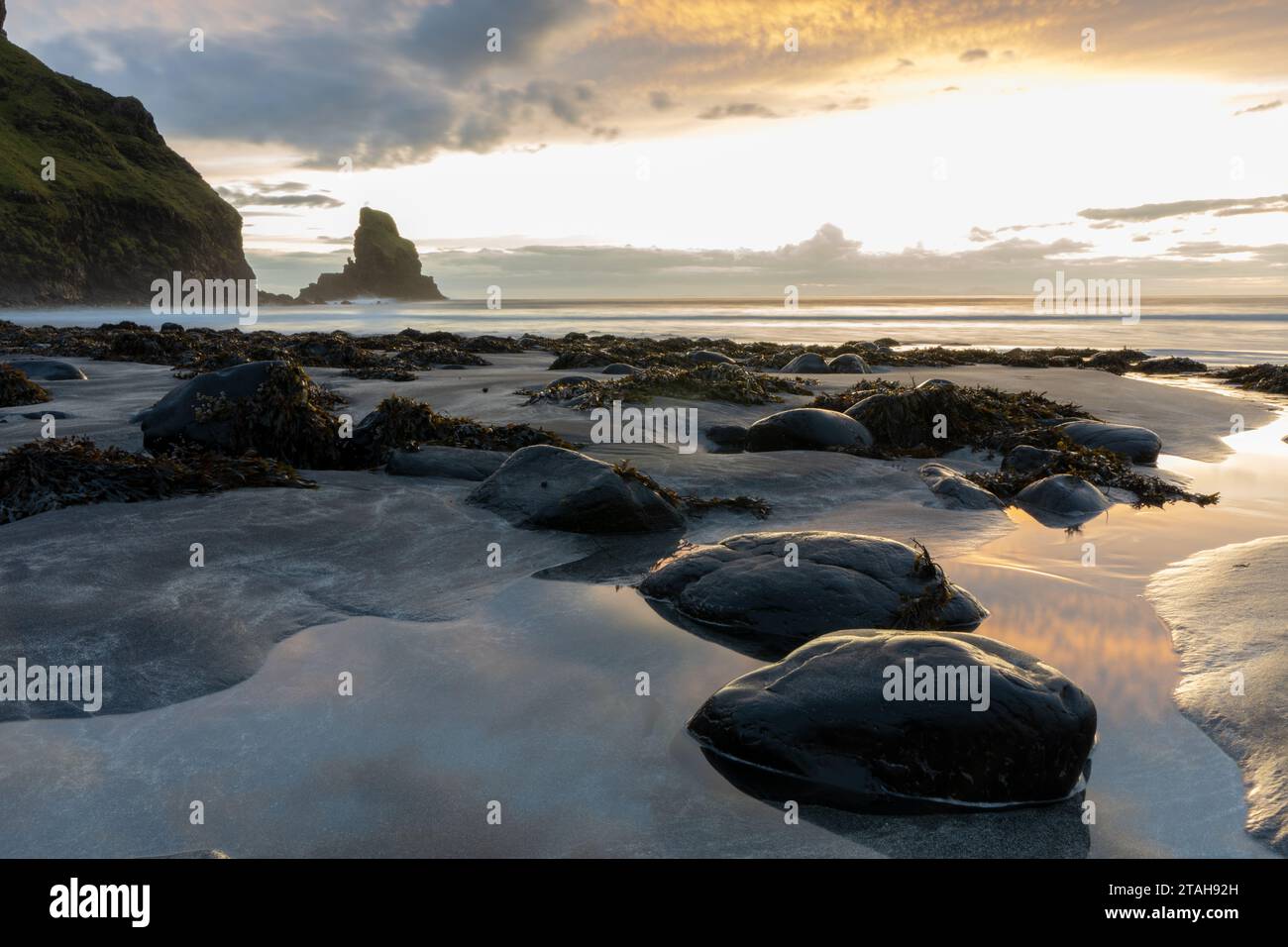 A stunning sunset over a beach with rocky terrain Stock Photo - Alamy