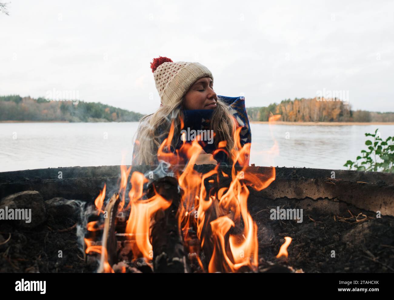 woman wrapped in a blanket getting warm by a fire in the forest Stock ...