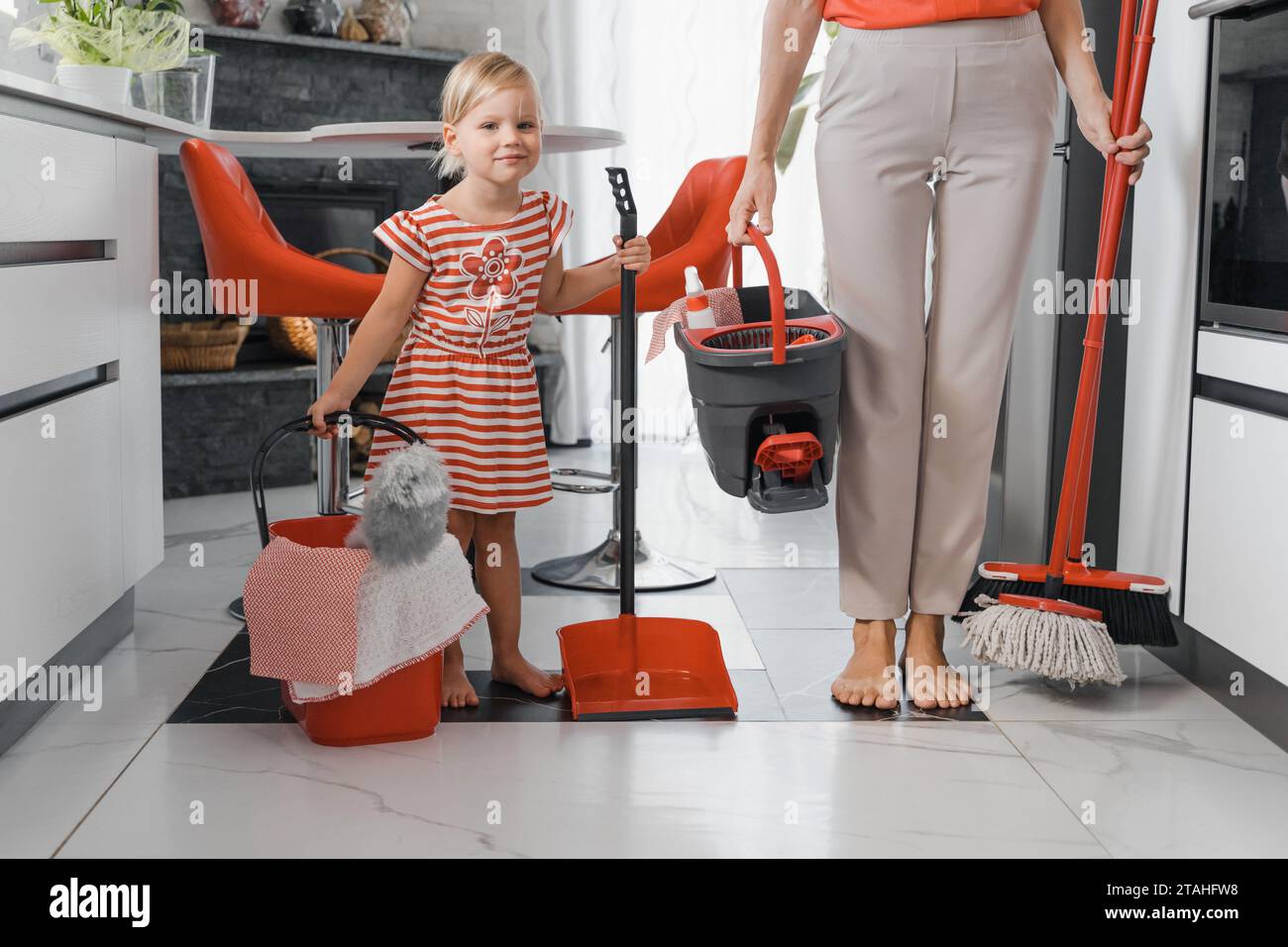 Mom and daughter are going to clean the house, holding mops, buckets ...