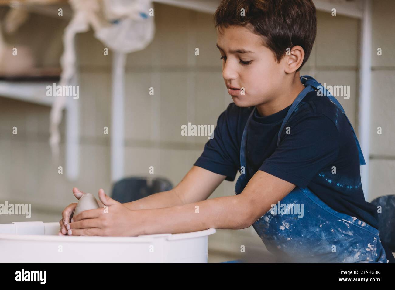 Young boy using hands to shape clay on pottery wheel Stock Photo - Alamy