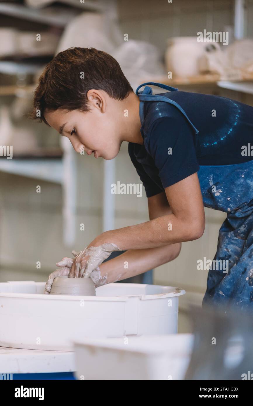 Young boy using hands to shape clay on pottery wheel Stock Photo - Alamy