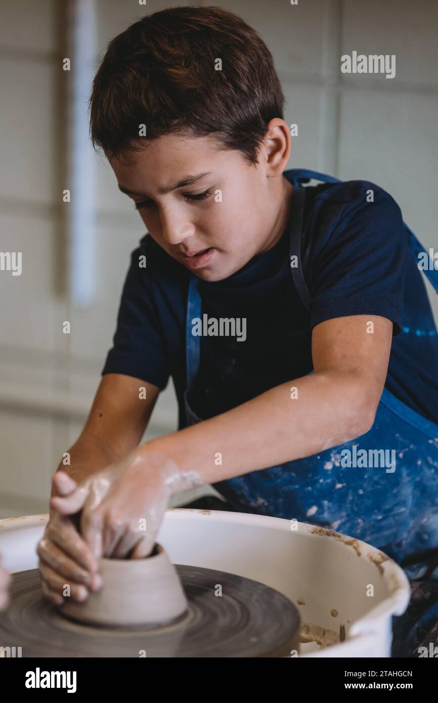 Young boy using hands to shape clay on pottery wheel Stock Photo - Alamy