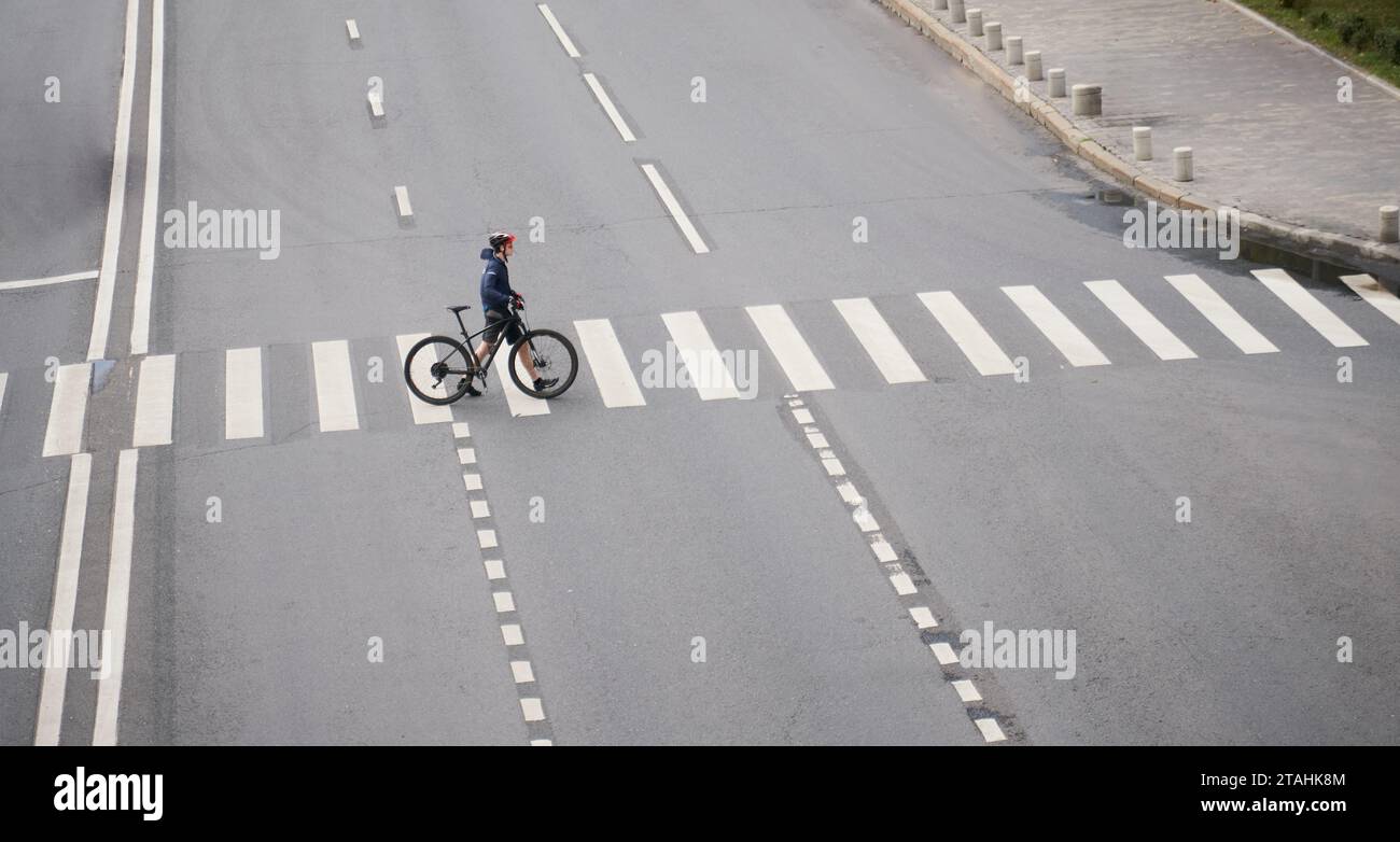 Man crosses the road at a pedestrian crossing and carries a bicycle ...