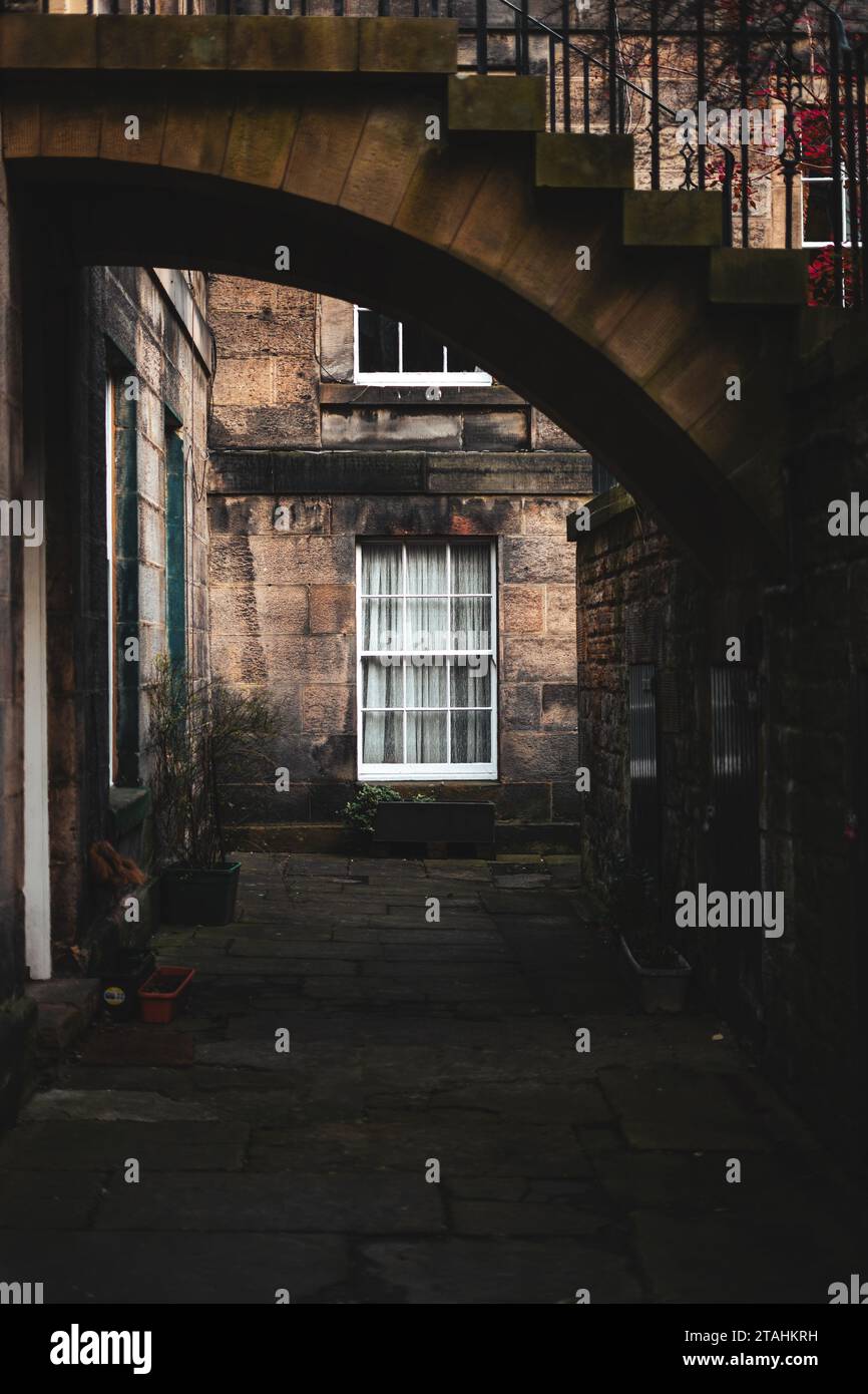A brick pathway leads between two buildings, with ornate iron railings ...