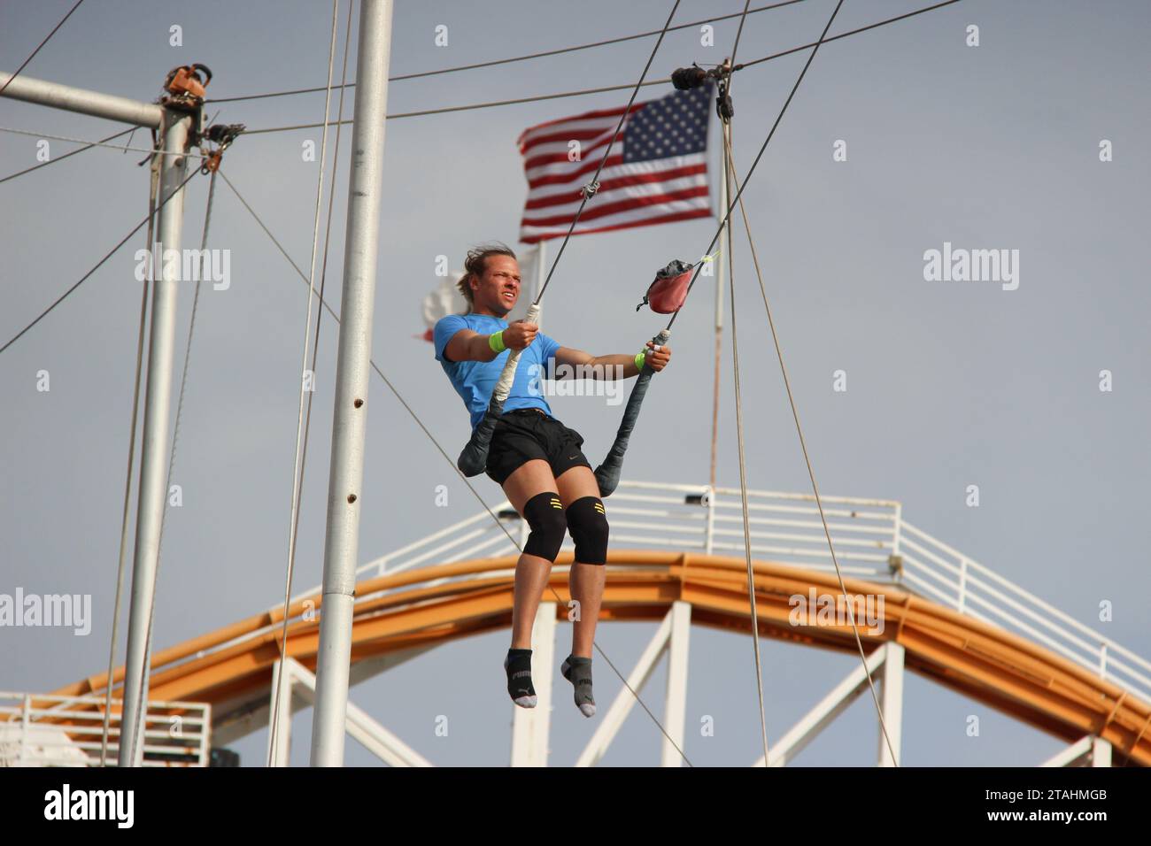 A young man doing gymnastics with the American flag in the background ...