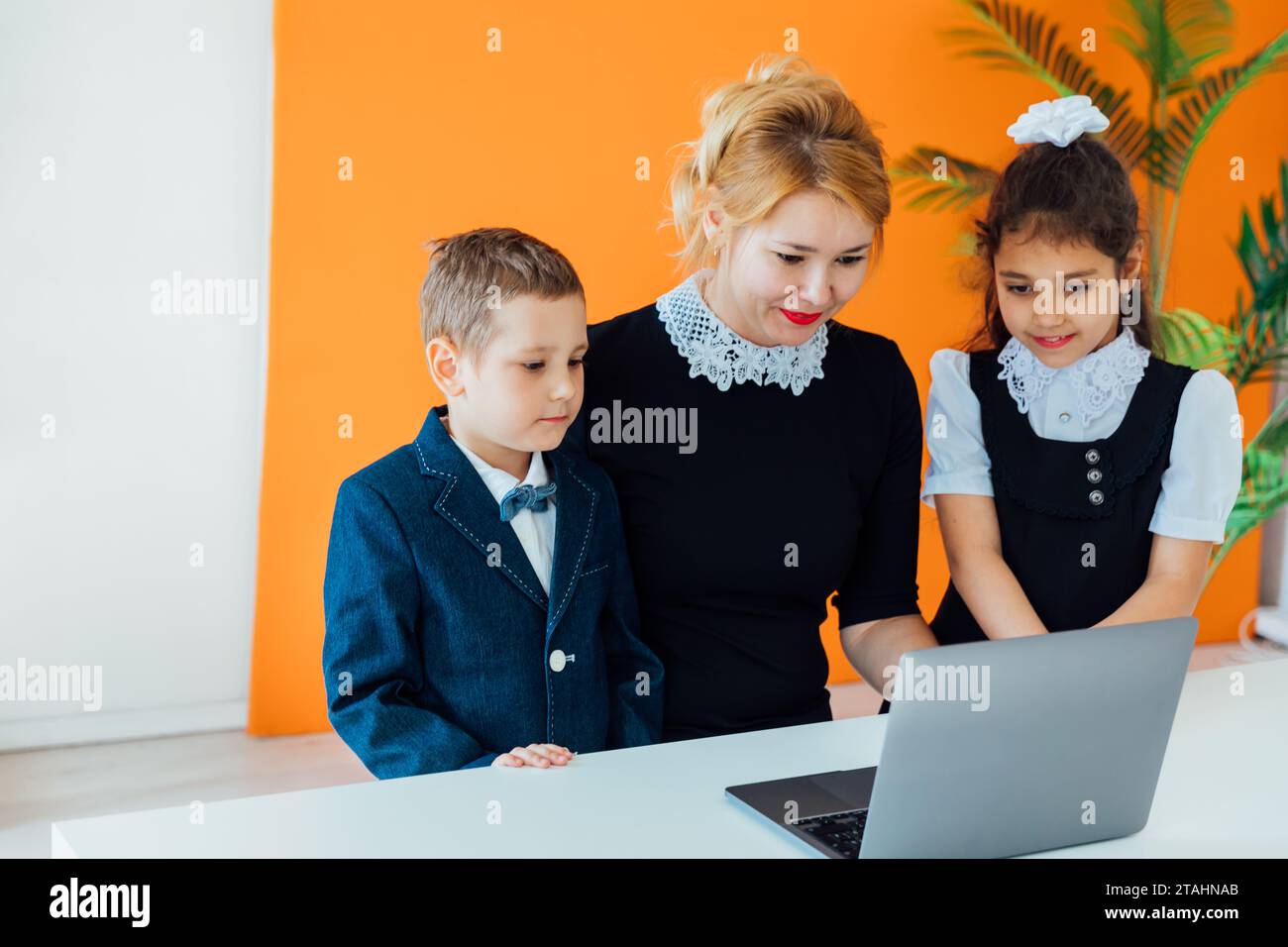 Teacher teaching boy and girl on computer at school Stock Photo - Alamy