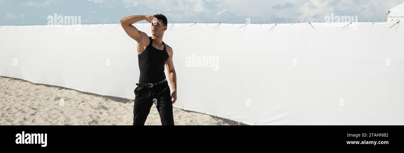 muscular cuban man in black outfit covering face with hand in Miami ...