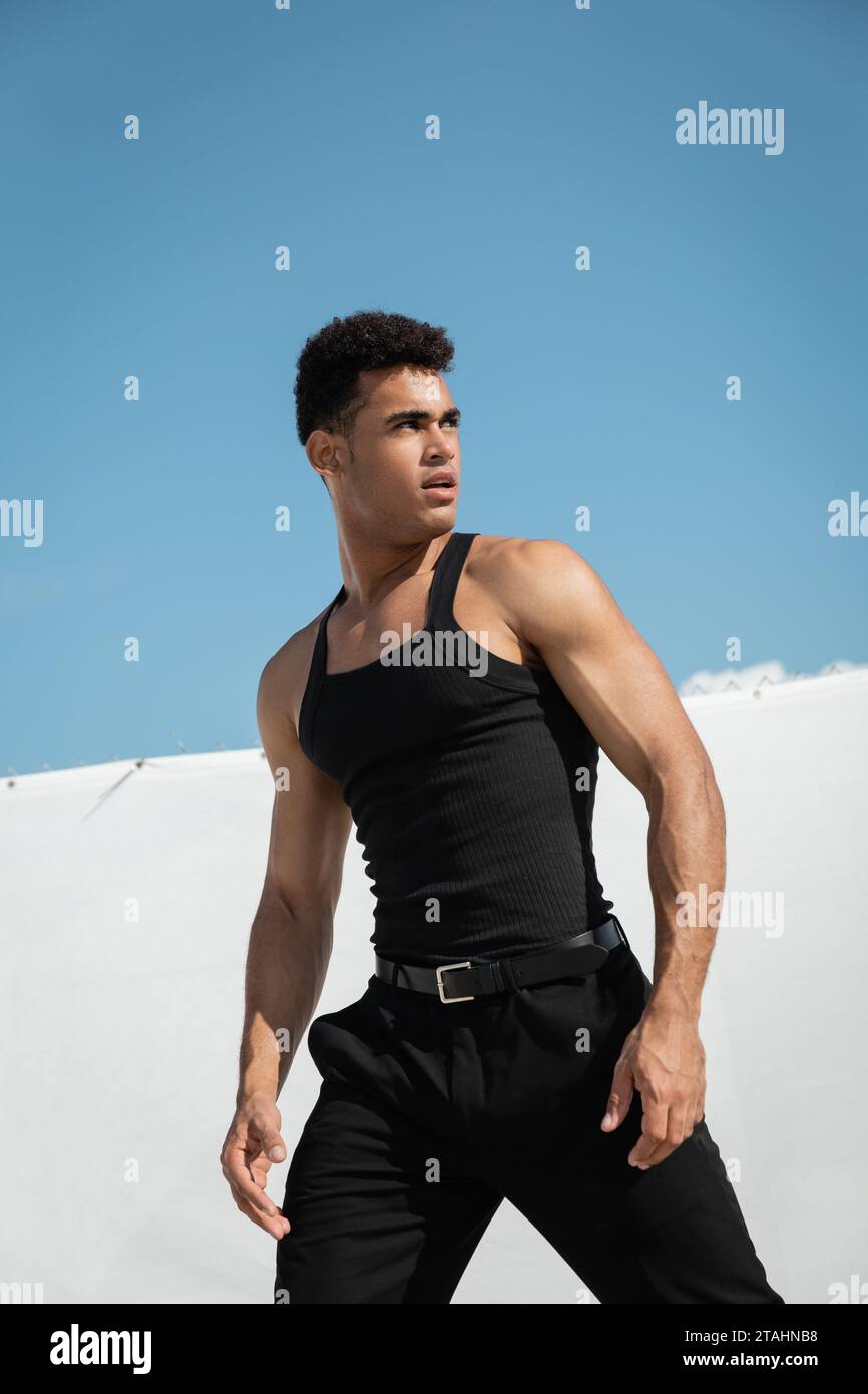 Portrait of strong and stylish cuban man in trendy black outfit looking ...