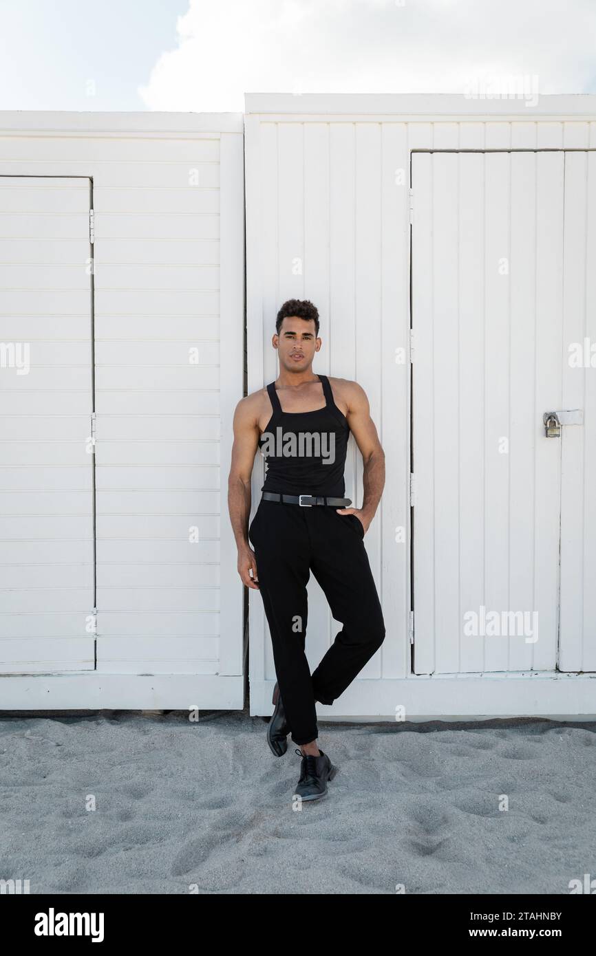 handsome young cuban man in black outfit posing and looking at camera ...