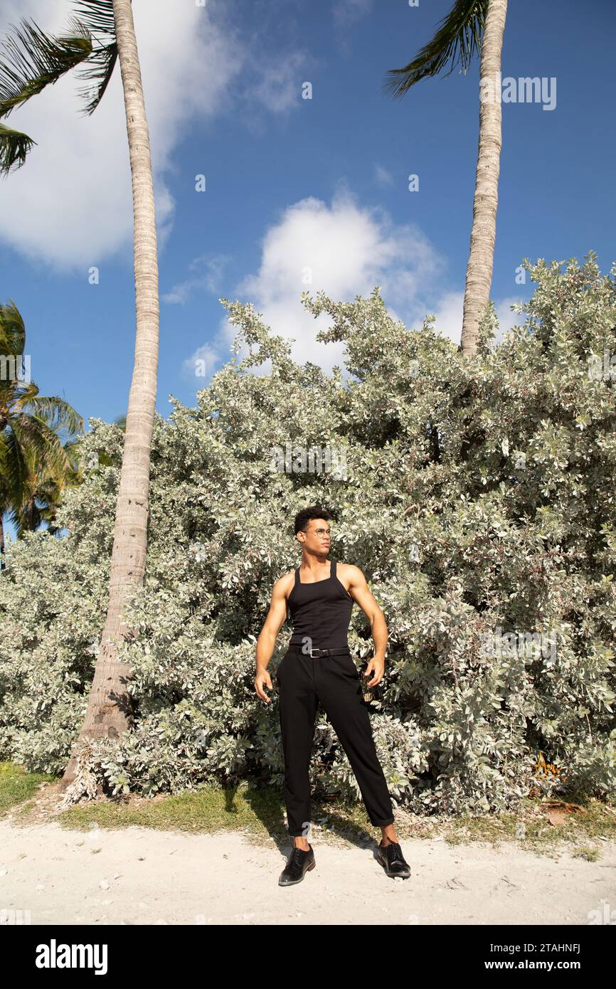 cuban man in black outfit and eyeglasses standing near palm trees on ...