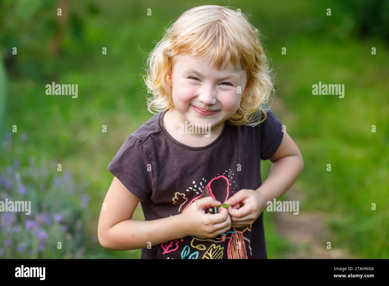 Little girl squinting her eyes while playing in the park in summer ...