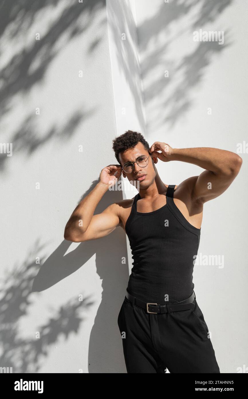 Fashionable cuban man standing near building with shadow on street in ...