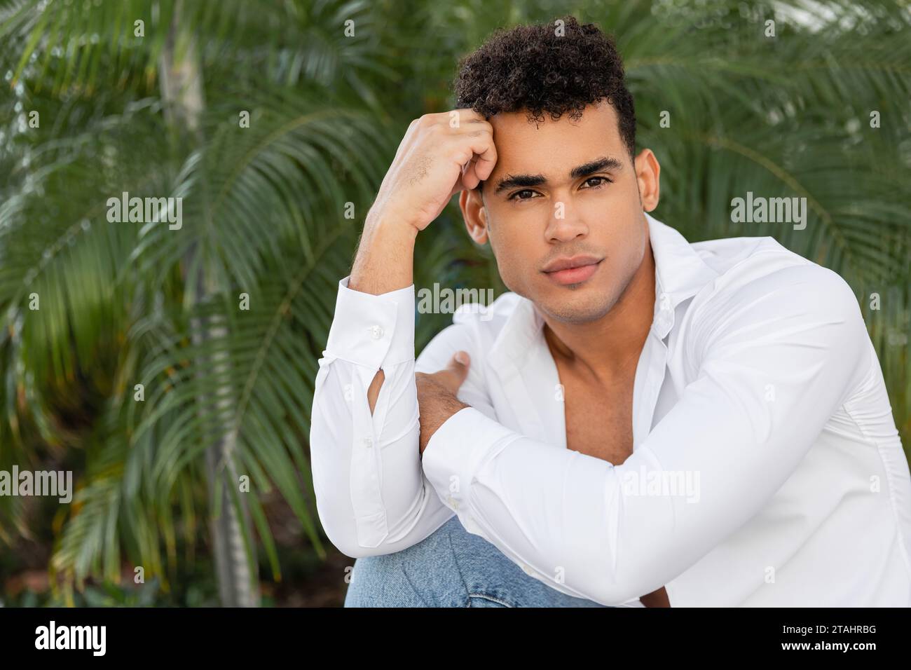Good looking and young cuban man with curly hair in white shirt and ...