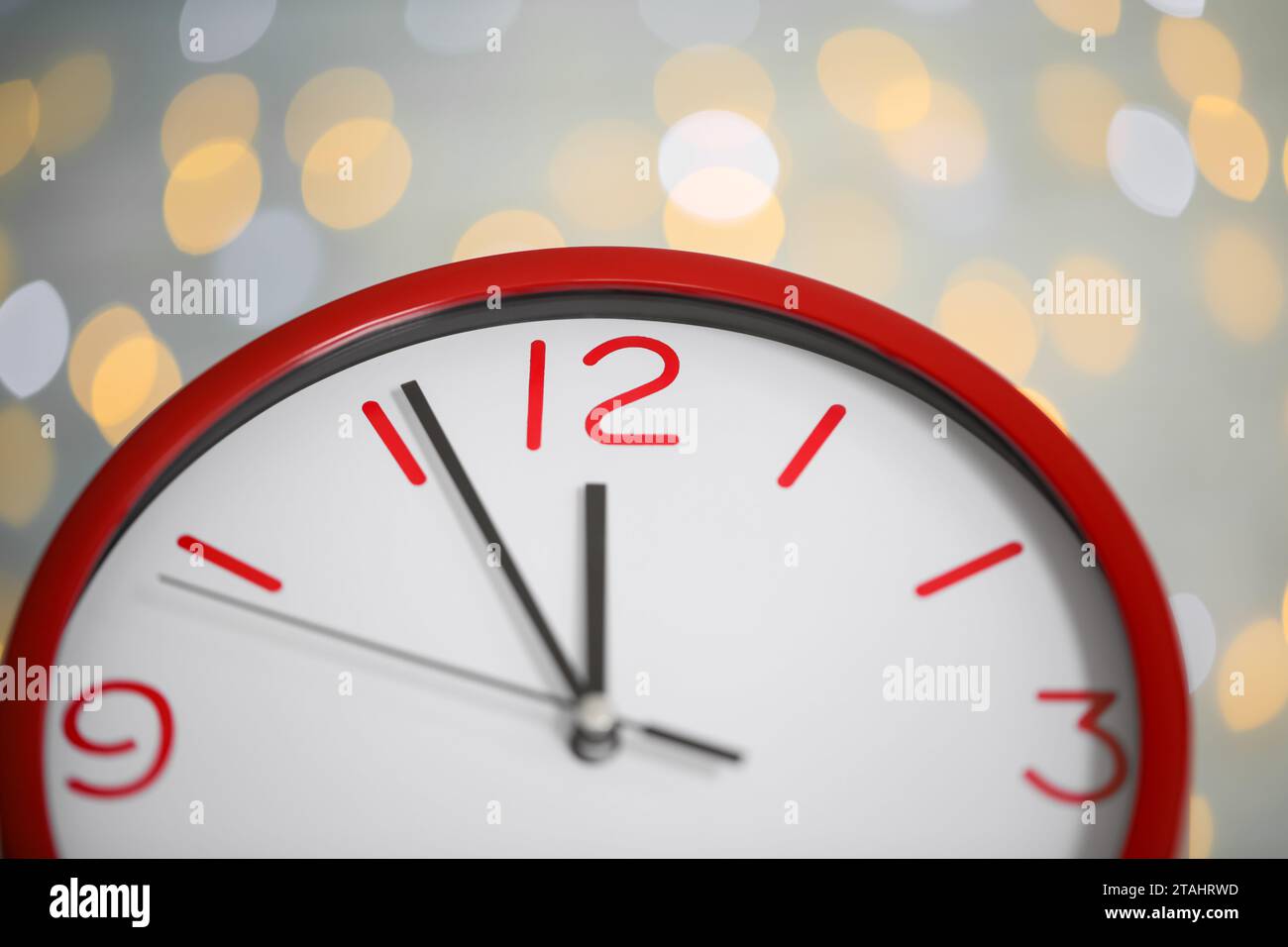Clock showing five minutes until midnight on blurred background ...