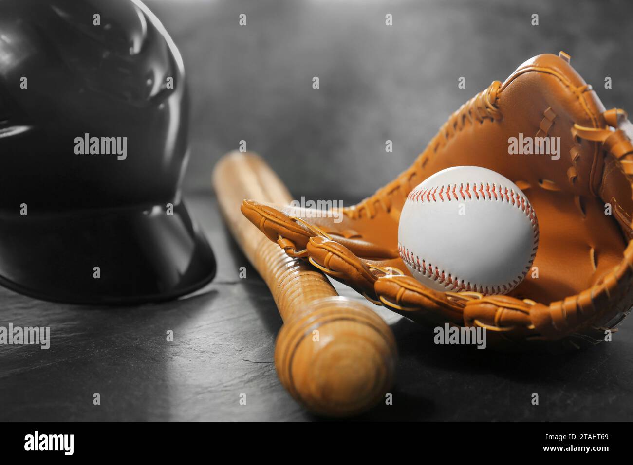 Baseball glove, bat, ball and batting helmet on black table, closeup ...