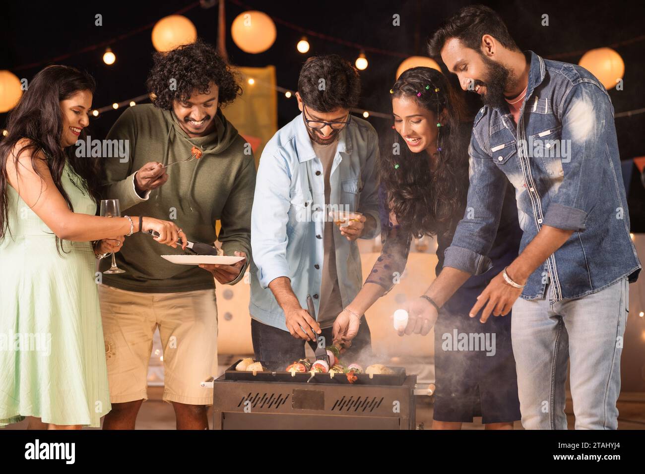 Group of friends busy cooking barbecue grills for dinner during night ...
