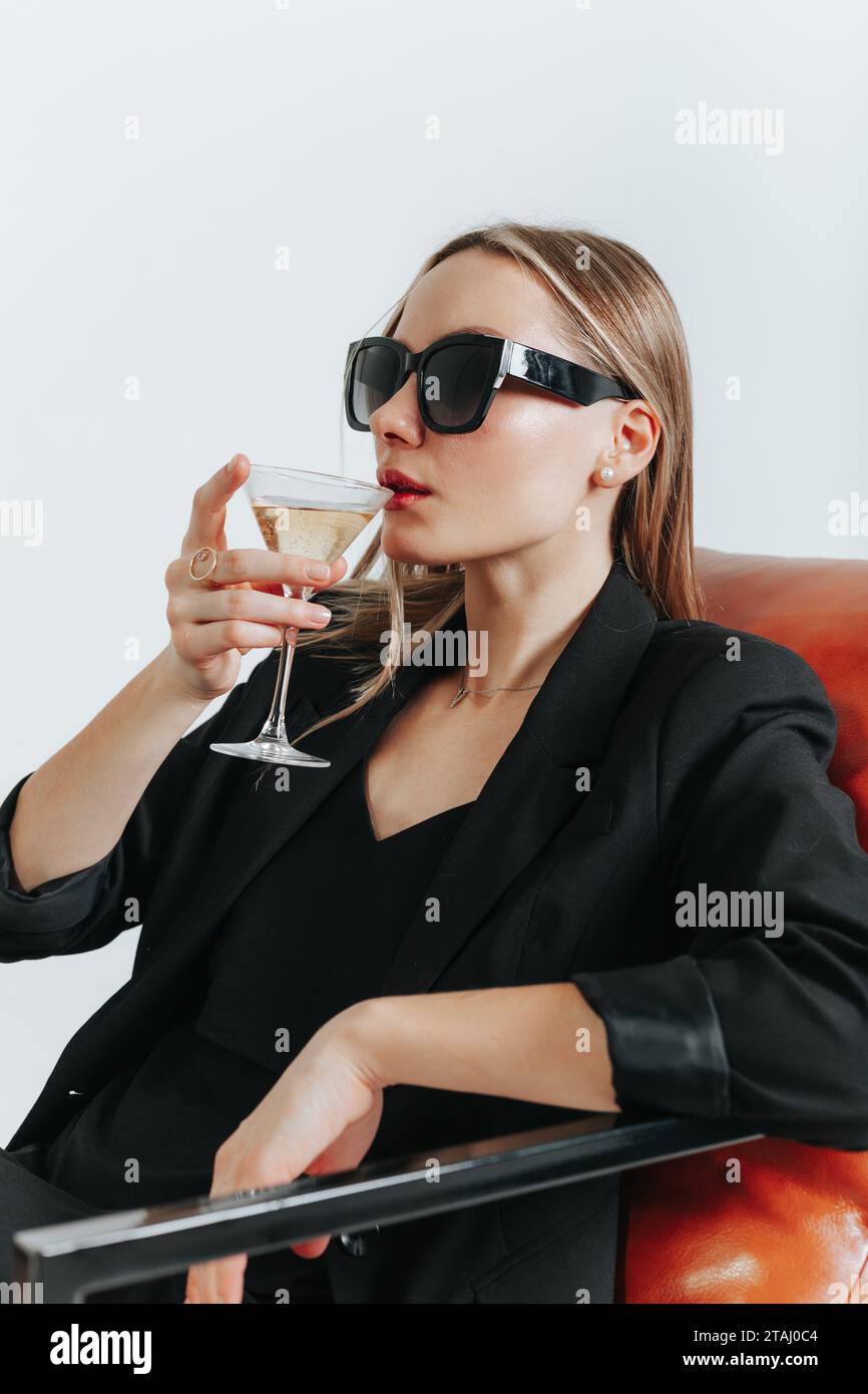 Lady boss in total black look sitting in armchair and drink wine ...