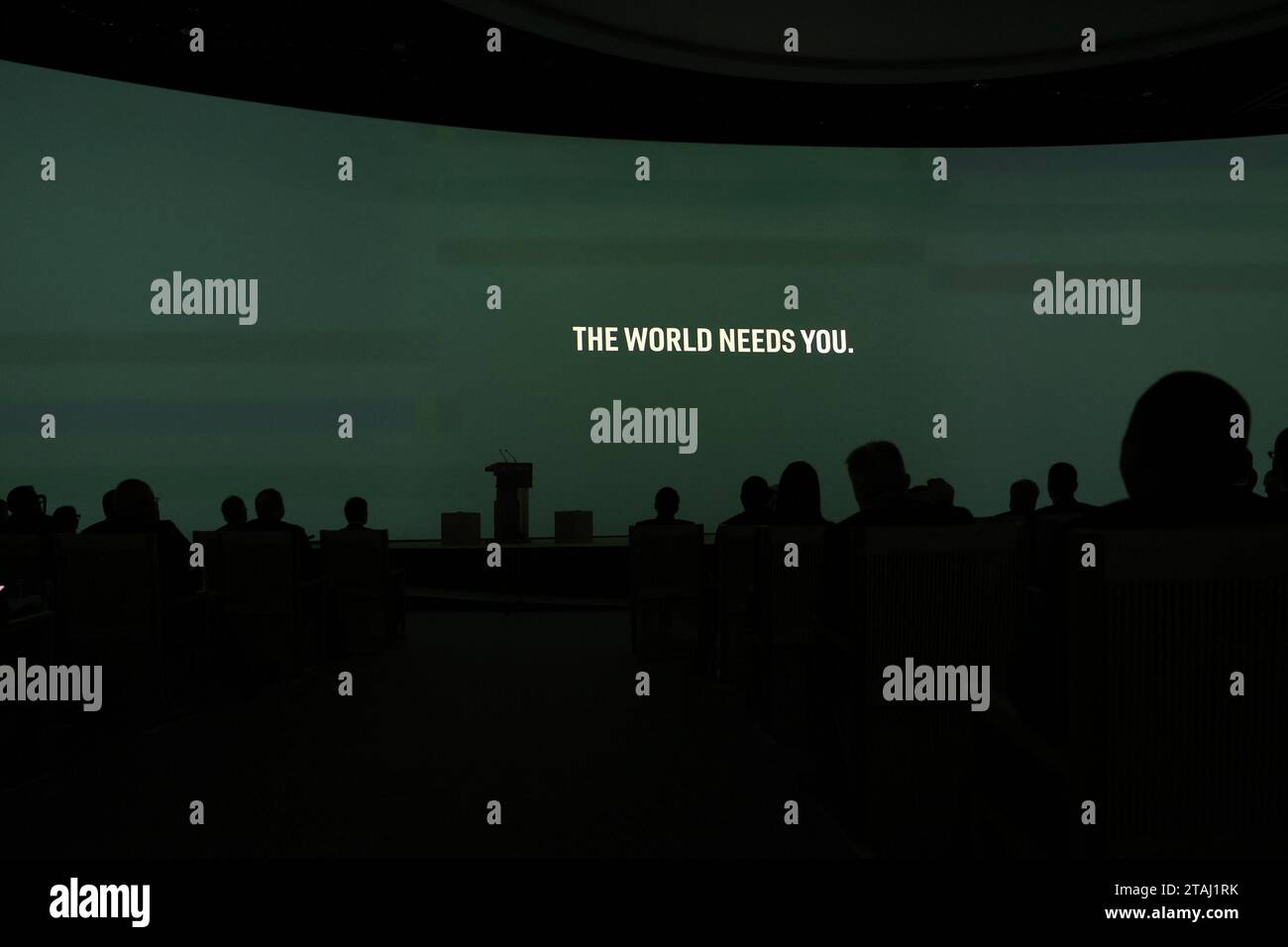 The words 'The World Needs You' are projected on screen at the opening ...
