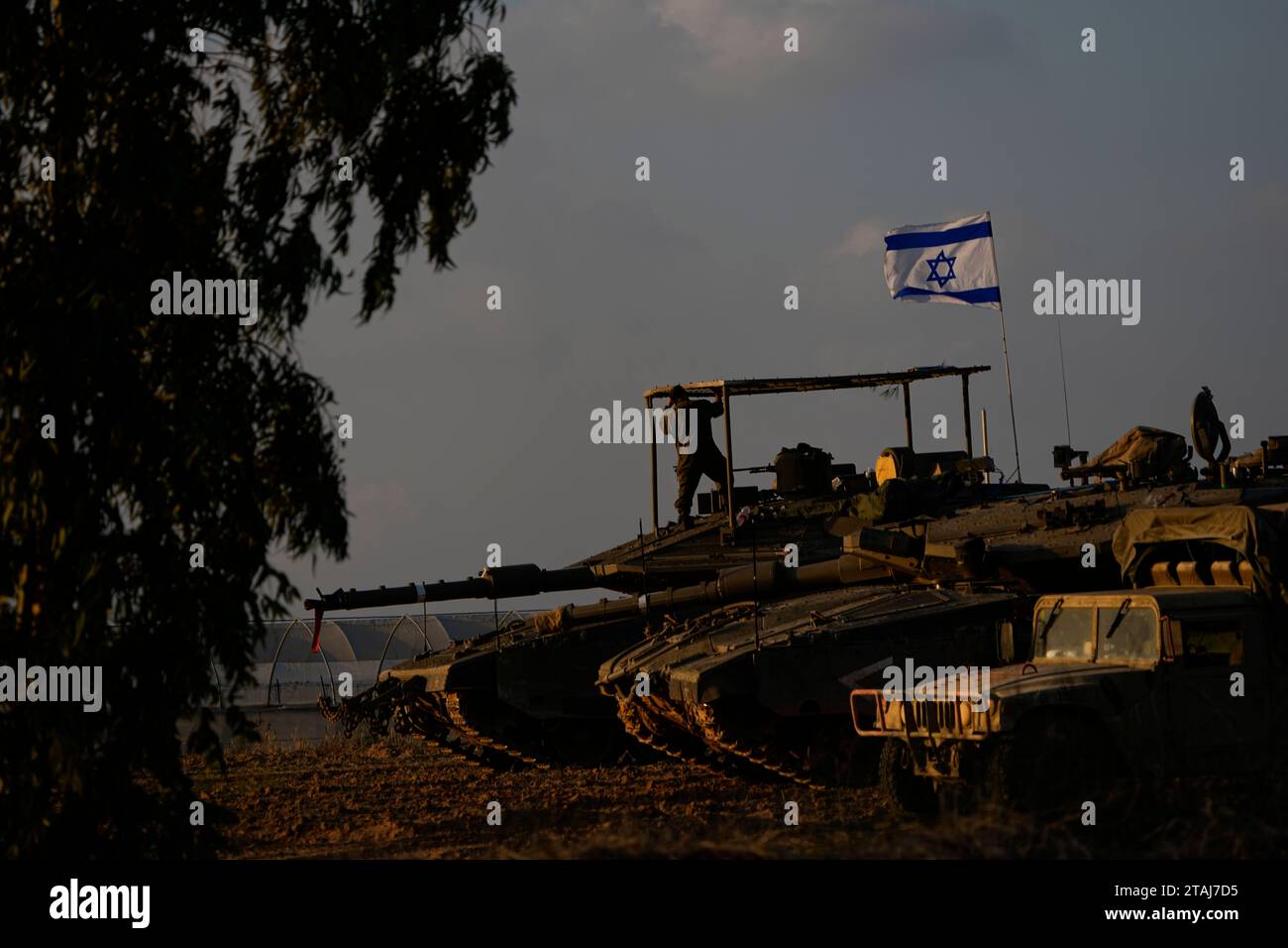 Israeli soldiers work on a tank at an army staging area near Israel's ...