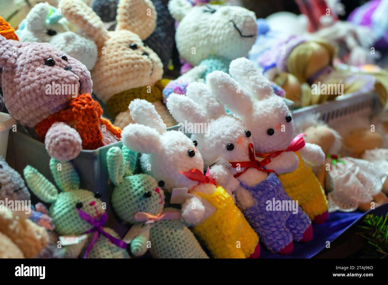 Colorful rabbits, handmade knitted toys lay on the counter in a gift ...