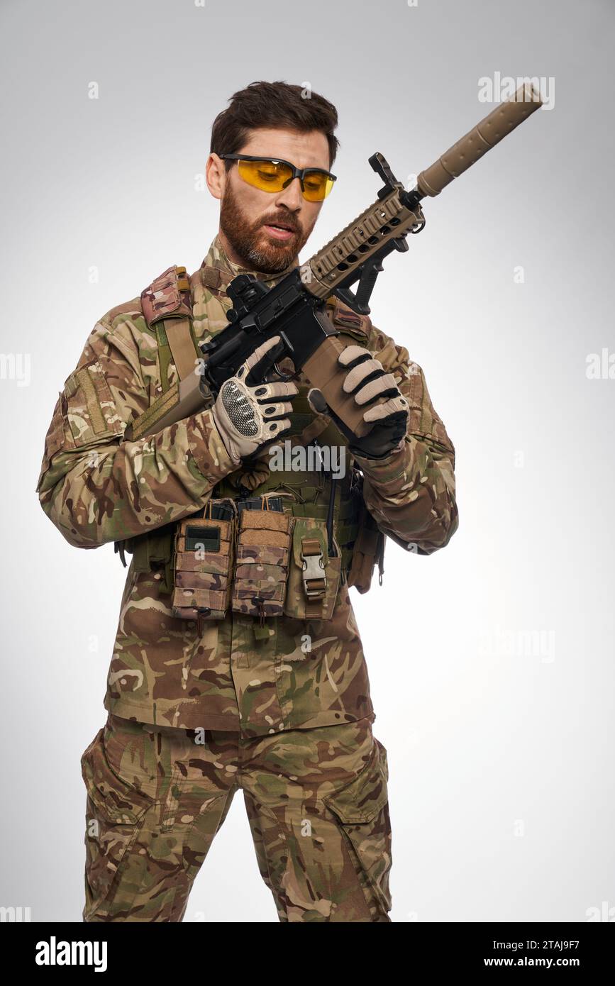 Focused male soldier in camouflage outfit recharging sniper rifle ...