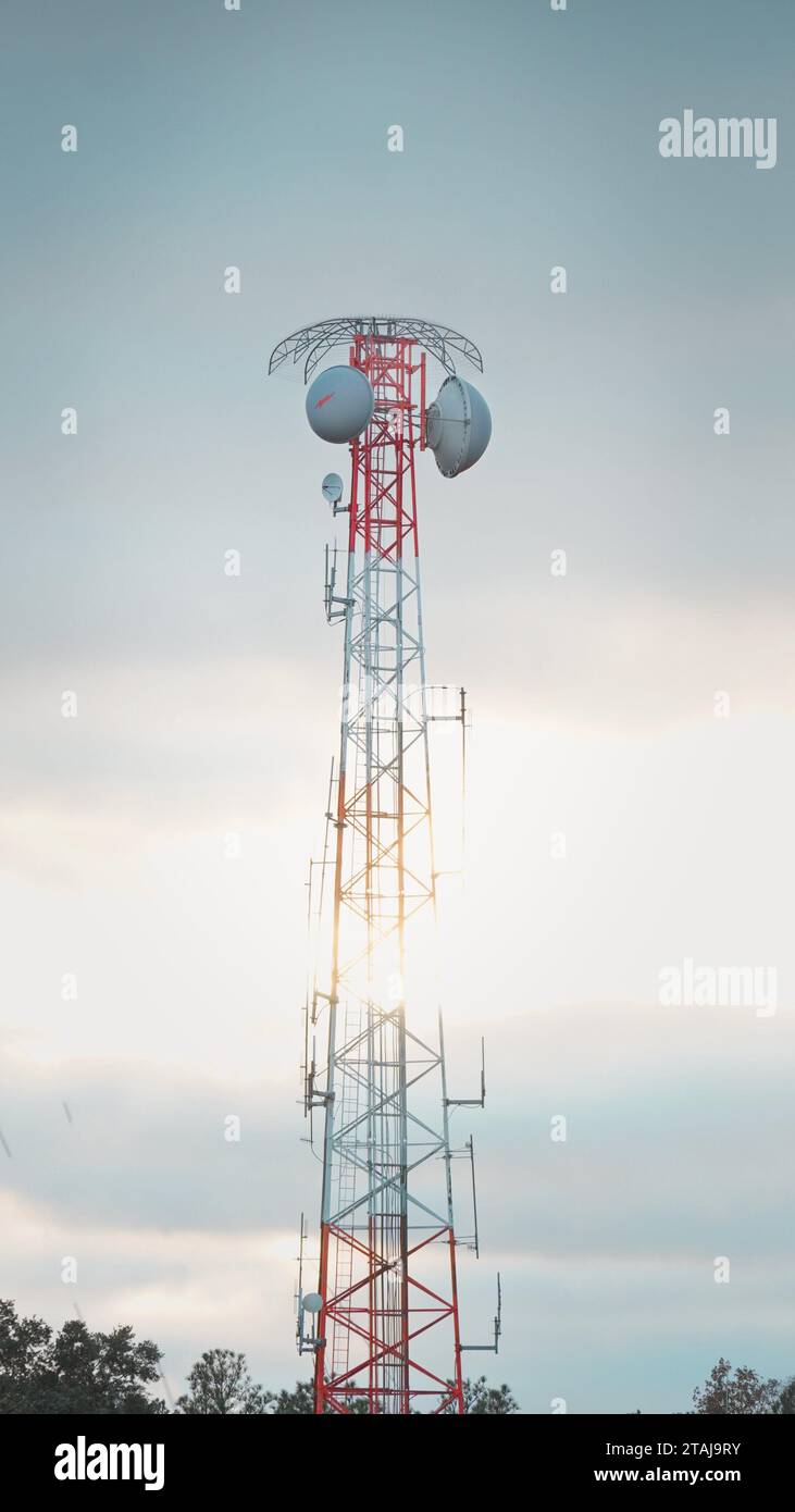 A tall radio tower with the sun setting in the background Stock Photo ...