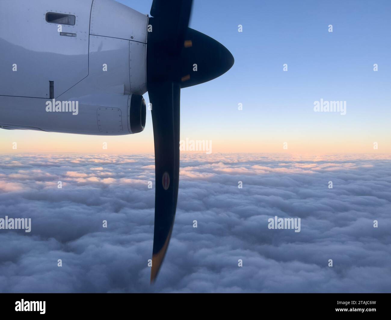 Rotating propeller of an airplane flying above the clouds in the sunset ...