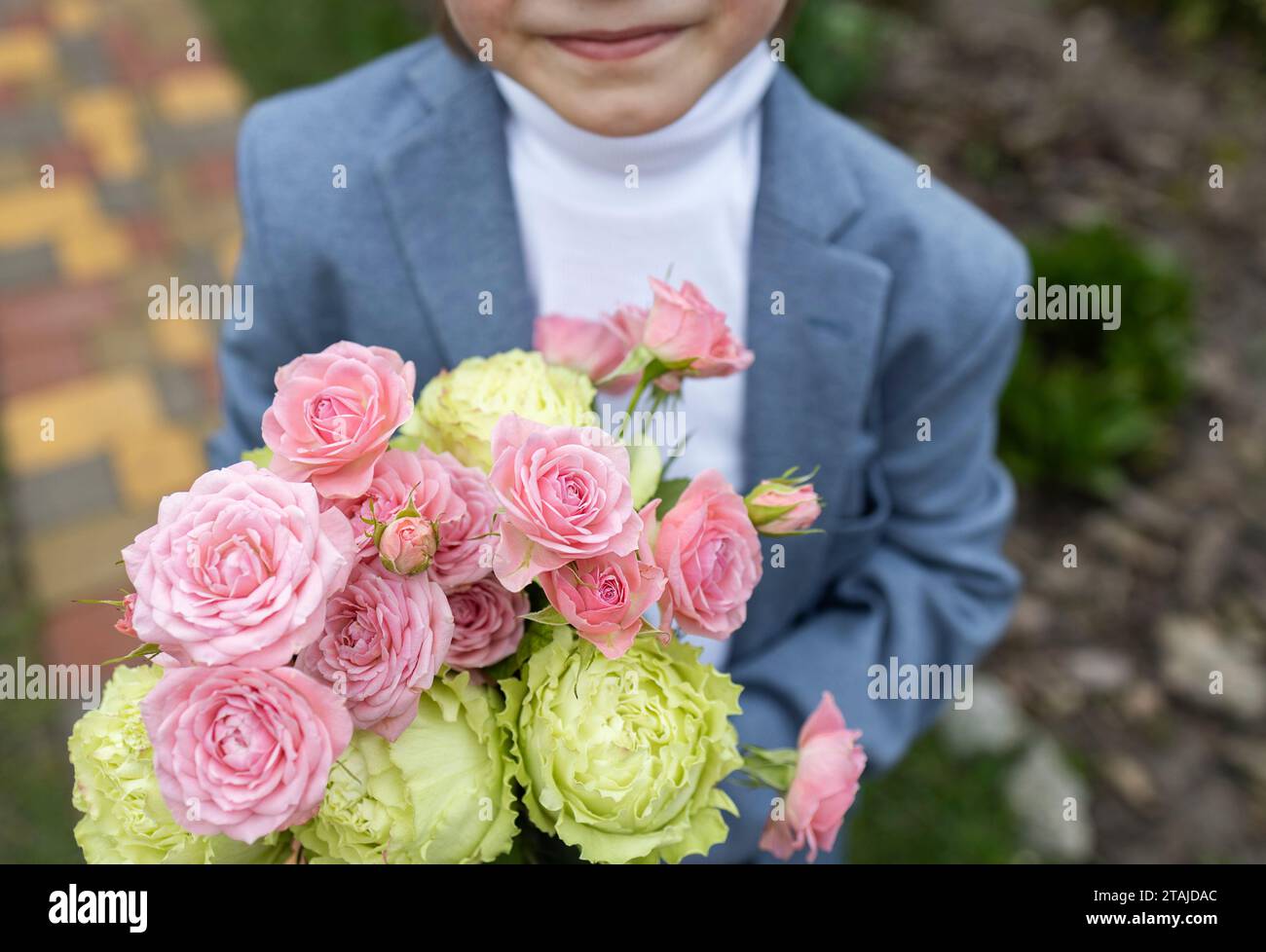 unrecognizable happy child holds a bouquet of pink and green roses in ...