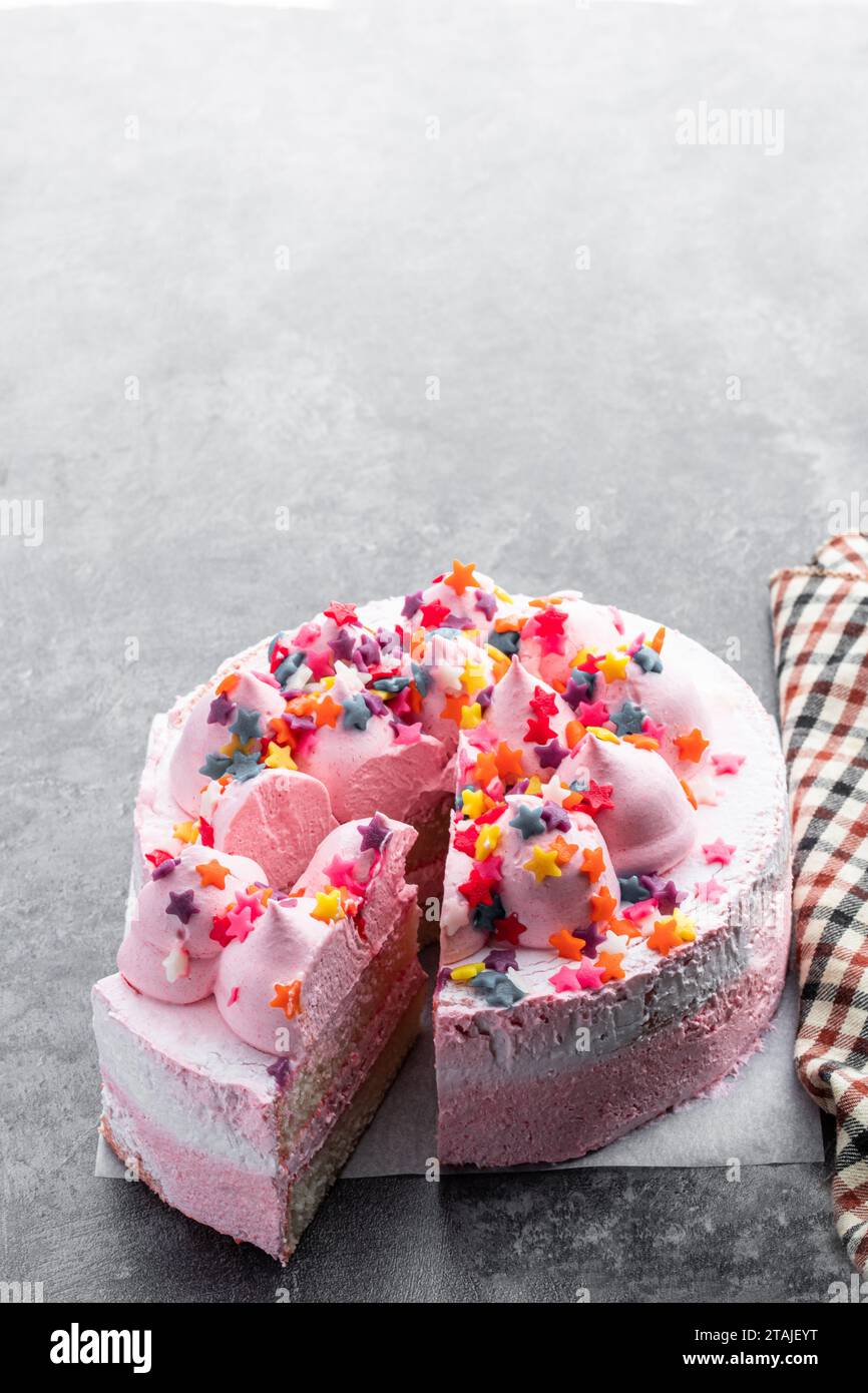 Pink Sponge cake decorated with small meringue on top on gray ...
