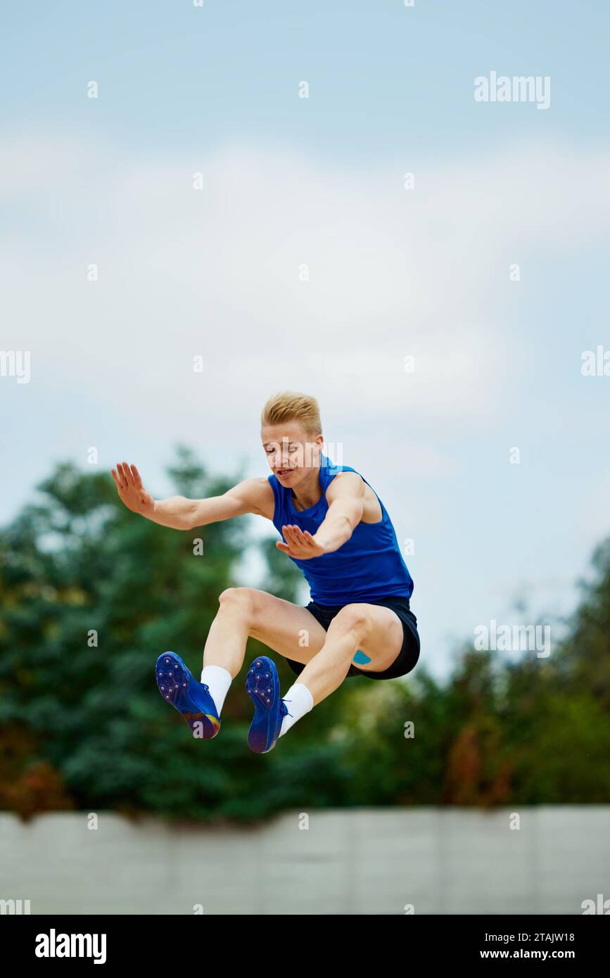 photo capturing climax of long jump, frozen in motion. Athletic man ...
